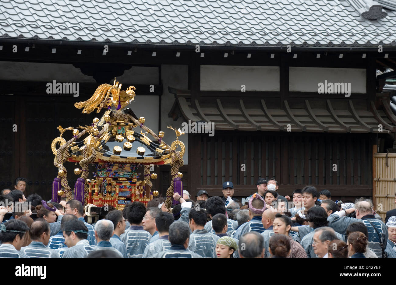 Men and women carry a gold decorated sacred mikoshi portable shrine in ...