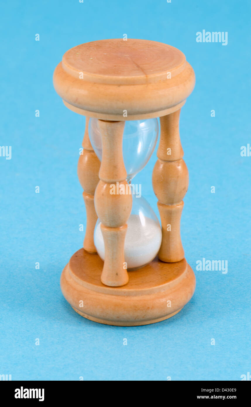 wooden retro sand glass clock stand on blue background. old timer ...