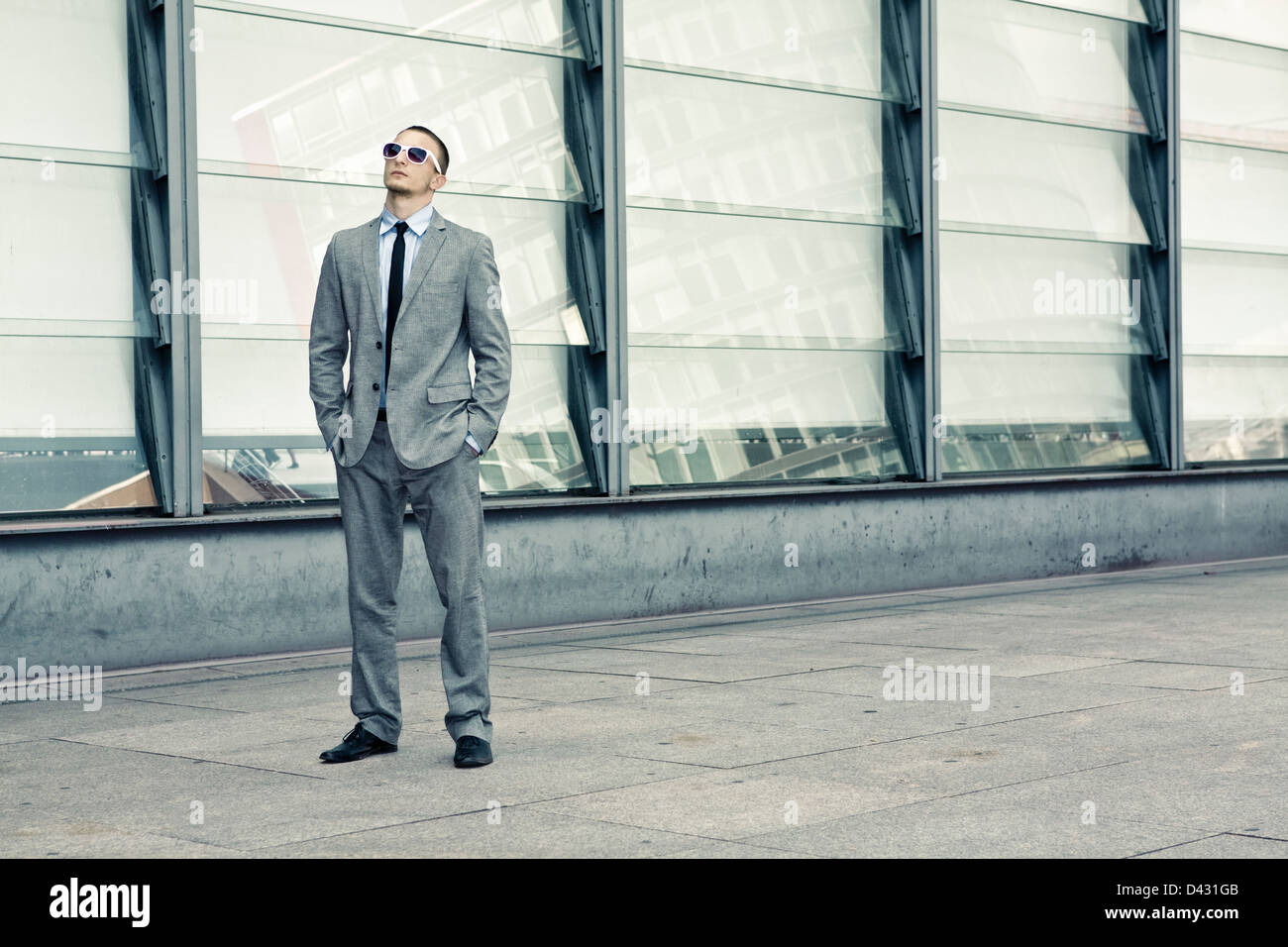 a man in suit standing in a modern building with glass facade Stock ...