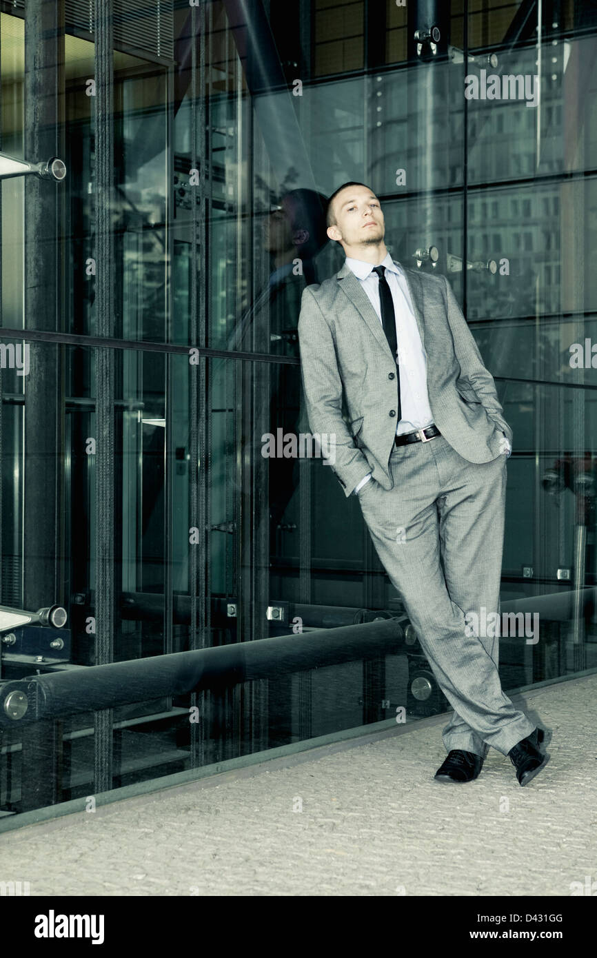 a man in suit leaning against the glass wall of a modern building Stock ...