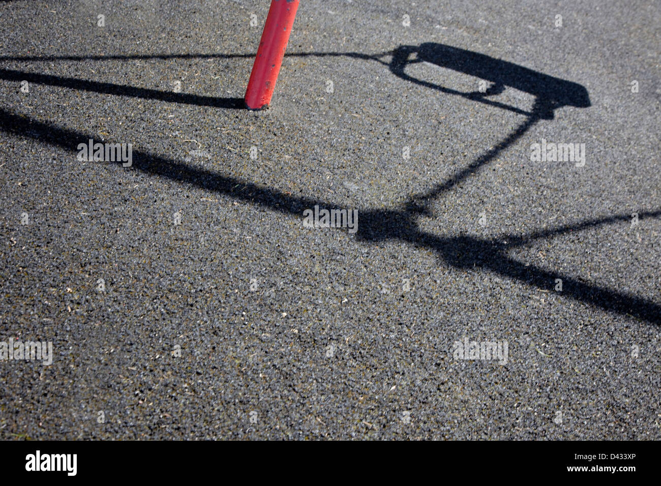 Shadow cast by the sun on the ground from an empty swing in a childrens ...