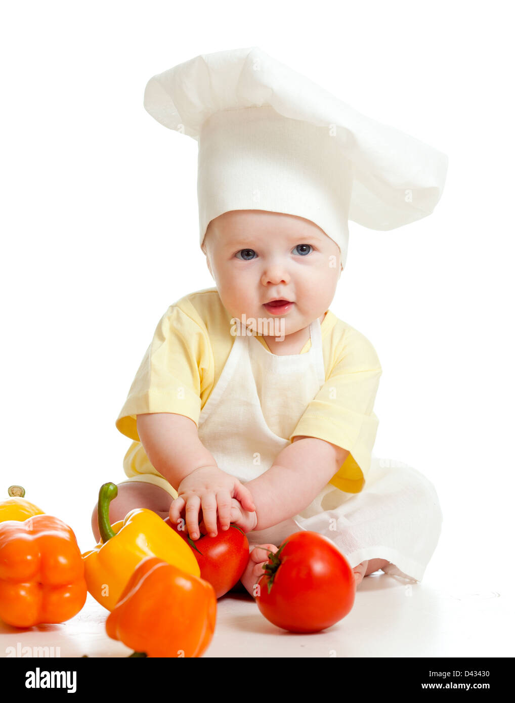 Portrait of a baby wearing a chef hat with healthy food vegetables ...