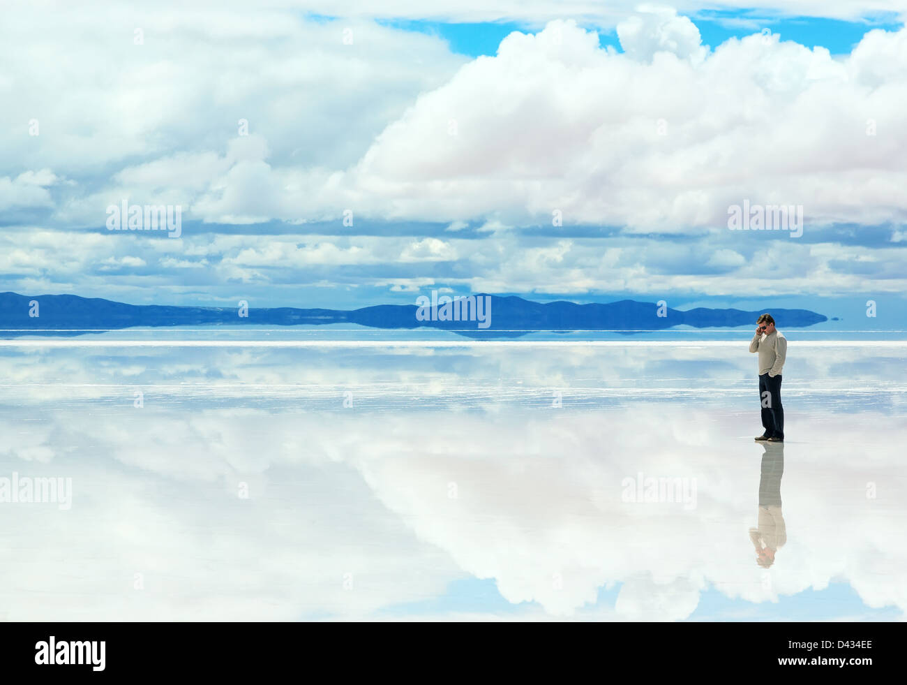 Man talking on the mobile phone in the middle of lake Salar de Uyuni ...