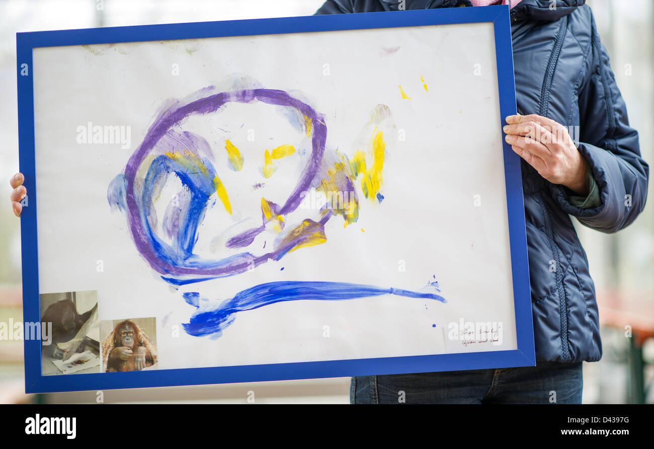 A woman holds an artwork painted by an ape at the zoo in Heidelberg ...