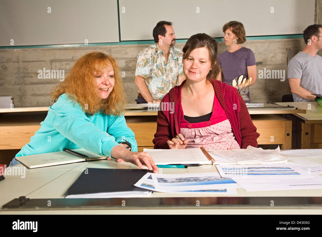 Two young female students discuss landscape drawings at drawing tables ...