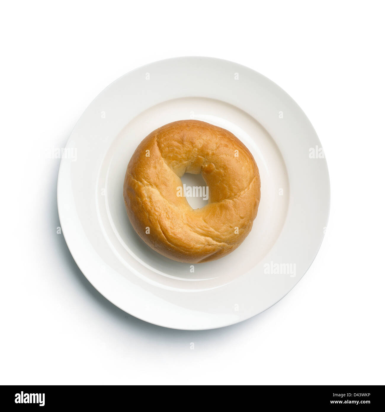 Single bagel on plate cut out white background Stock Photo - Alamy