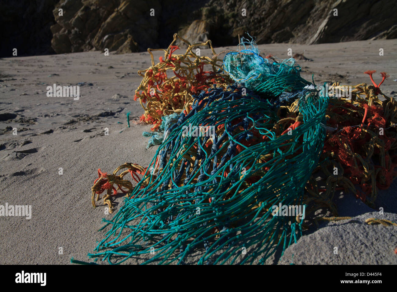 Brightly coloured tangled fishing nets washed up by the sea lie on the ...