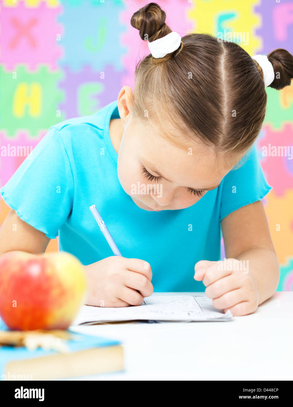 Cute little girl is writing using a pen Stock Photo - Alamy
