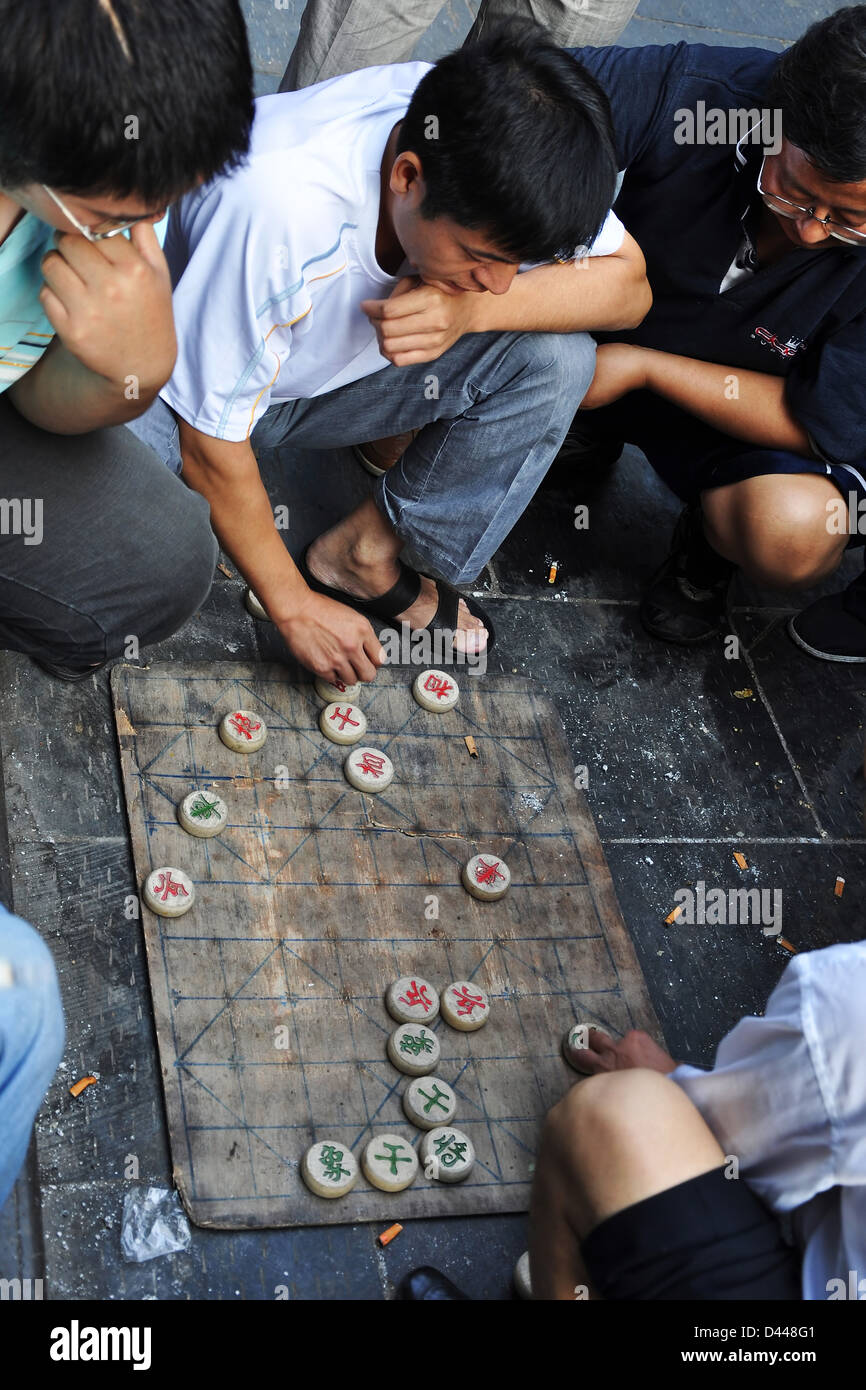 Chinese men playing chinese chess (xiangqi) on the floor in the street ...