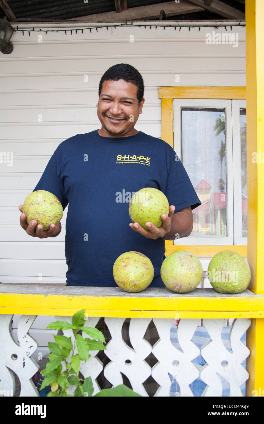 Panamanian man smiling and holding big, green, yellow exotic fruit ...