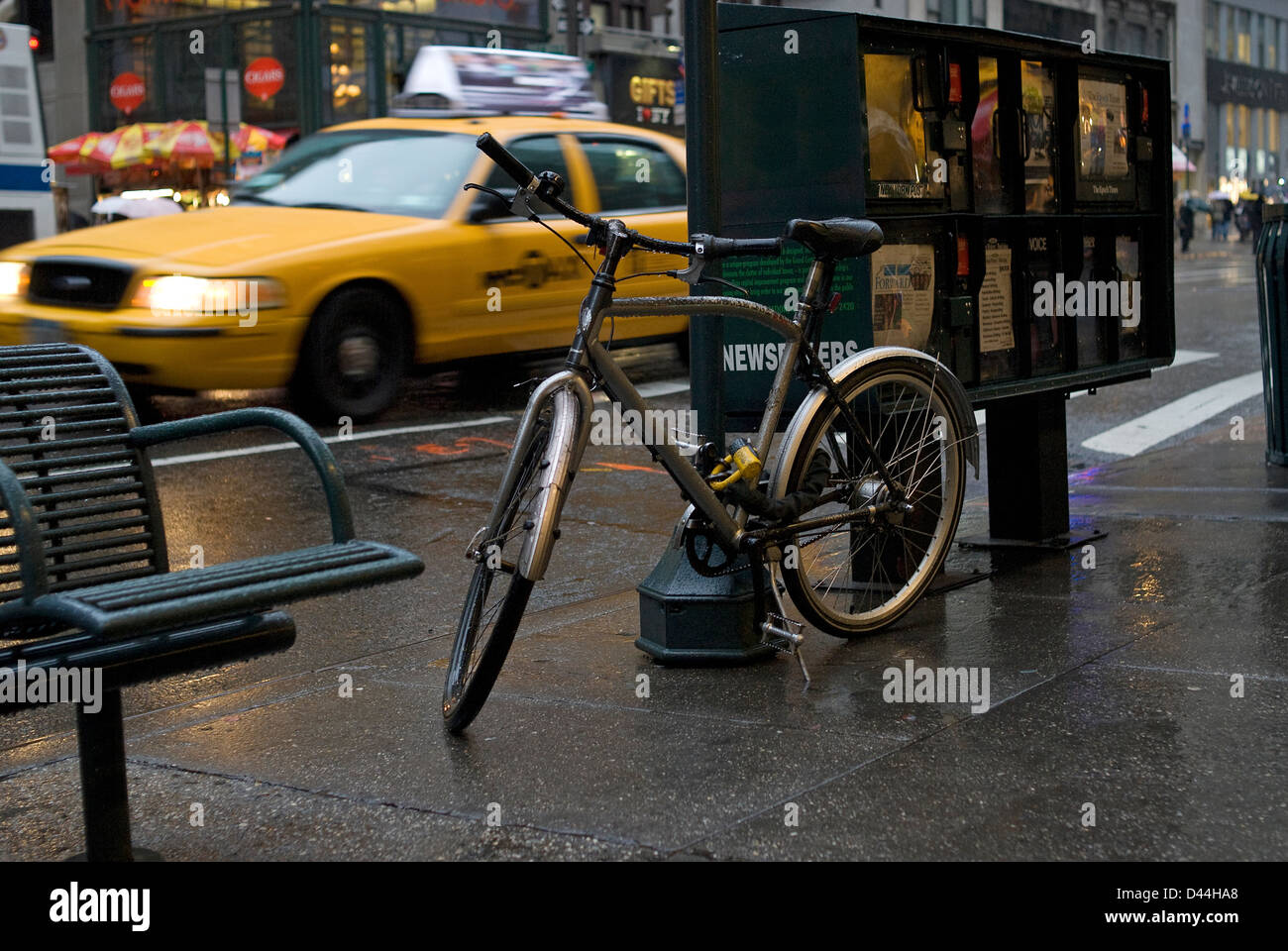 Gold colour bike attached at lamp post on wet New York City's street ...