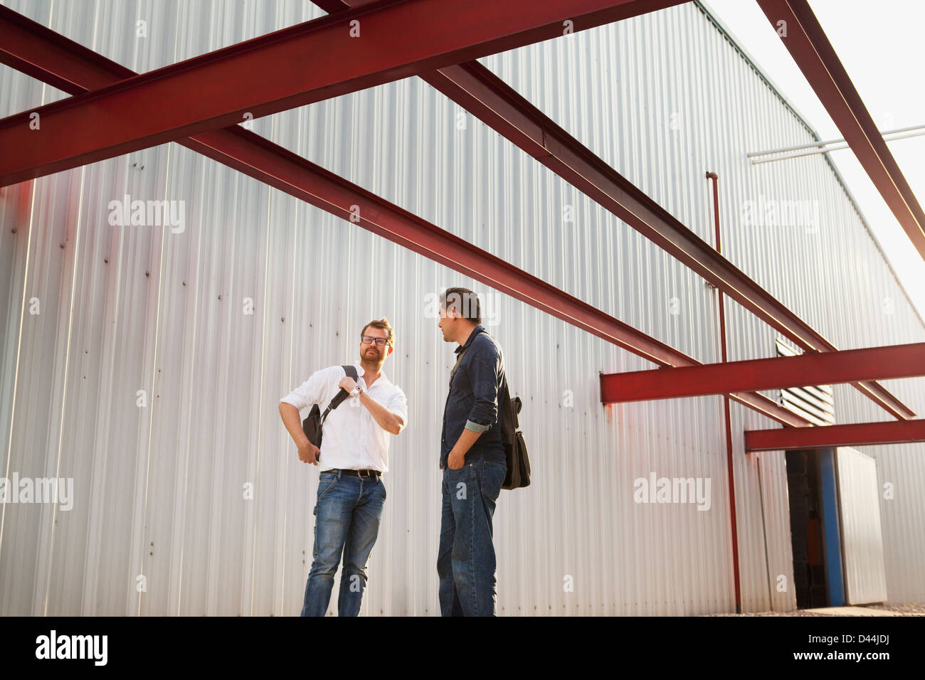 Men talking outside manufacturing plant Stock Photo - Alamy