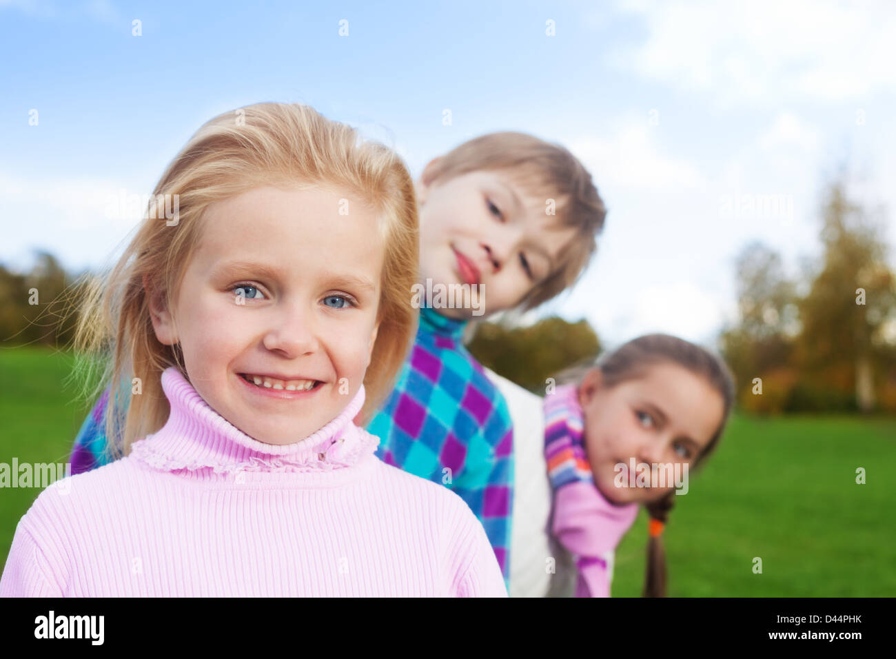 three kids having fun after school in the autumn park Stock Photo - Alamy