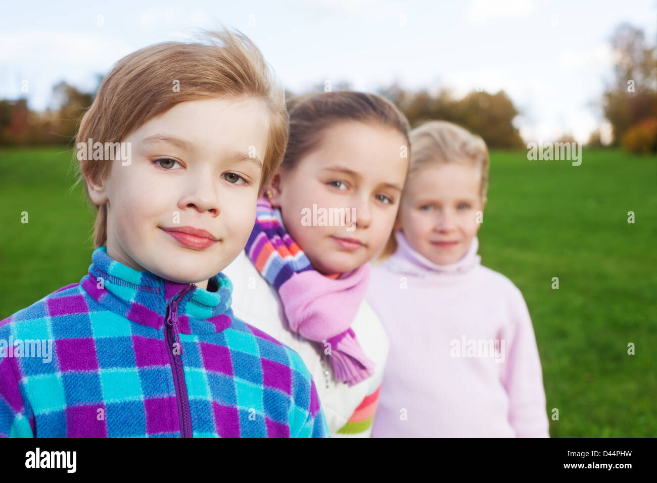 three kids standing in line in the park Stock Photo - Alamy