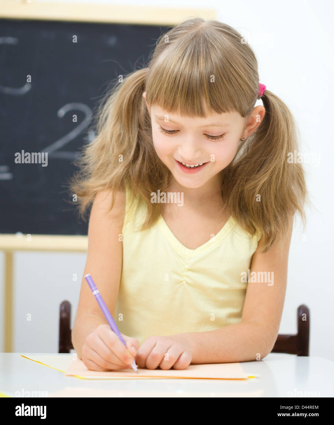 Cute little girl is writing using a pen in preschool Stock Photo - Alamy