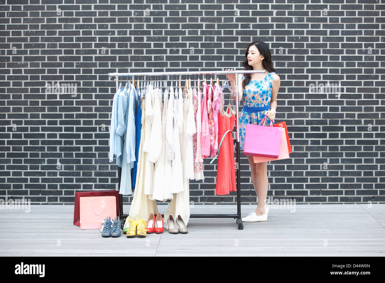 a girl with a shopping bag next to a clothing rack Stock Photo - Alamy