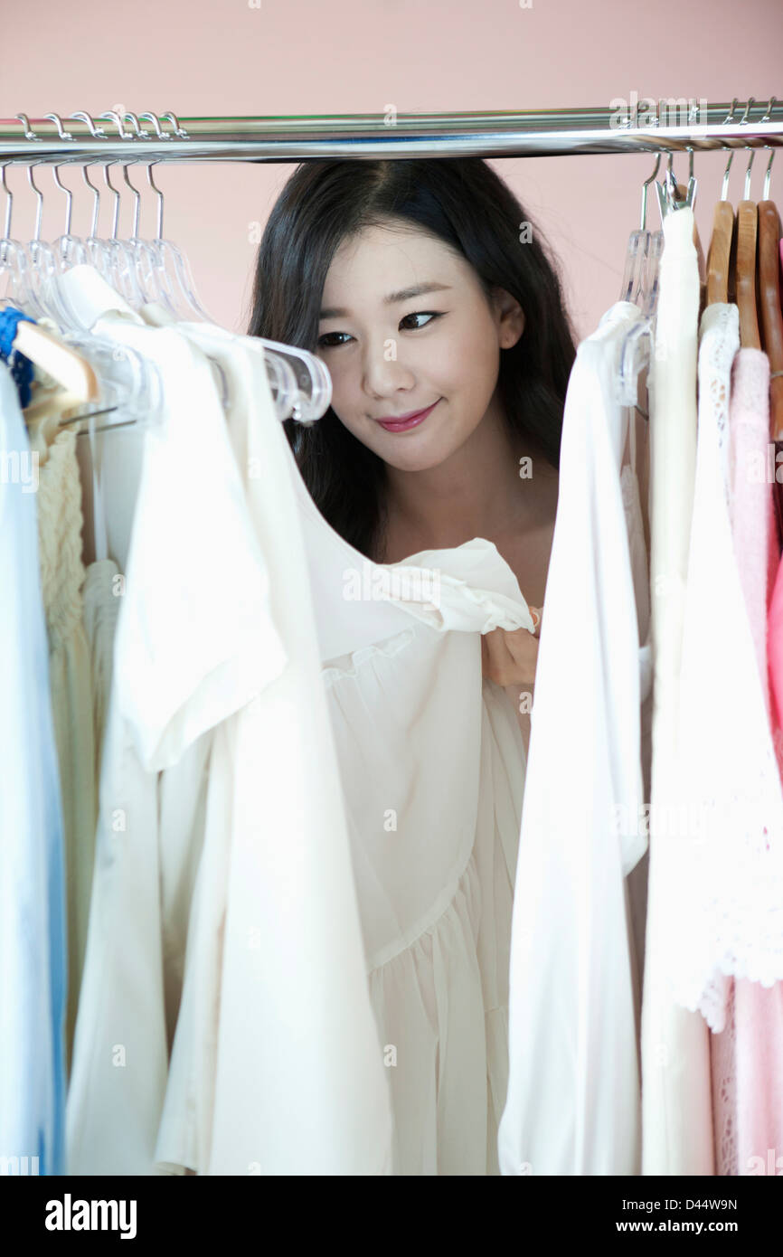 a girl looking through clothes in a clothing rack Stock Photo - Alamy