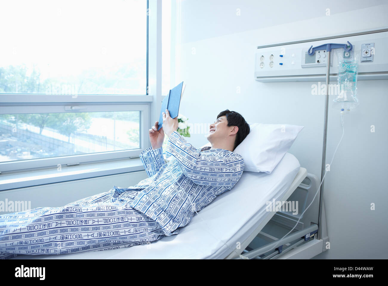 a patient lying on the bed reading a book in hospital room Stock Photo ...