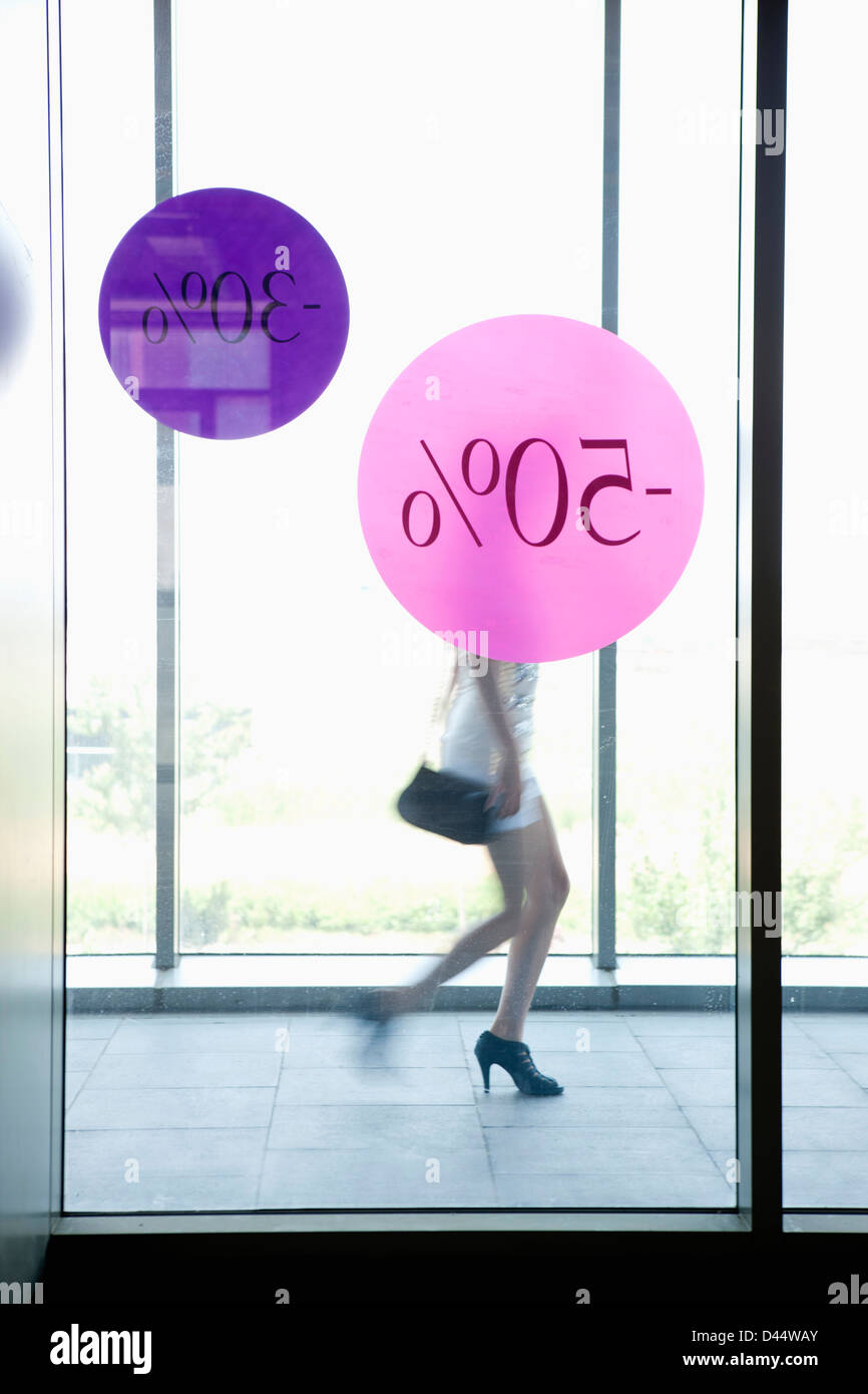 a woman walking along a shopping window with sale sign Stock Photo - Alamy