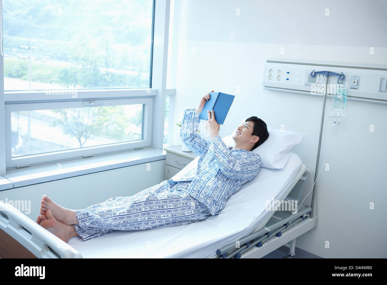 a patient lying on the bed reading a book in hospital room Stock Photo ...