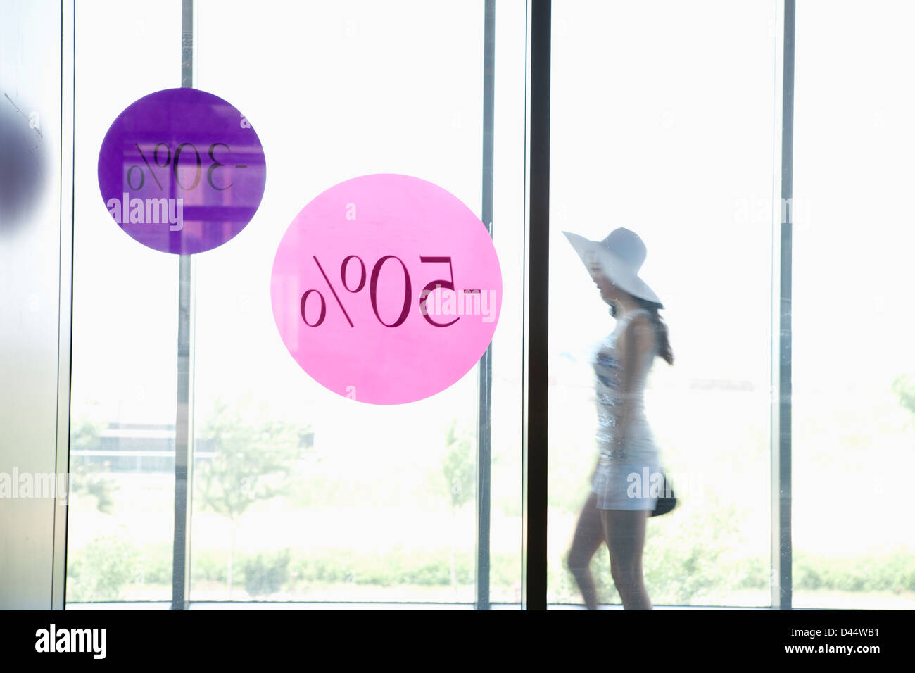 a woman walking along a shopping window with sale sign Stock Photo - Alamy