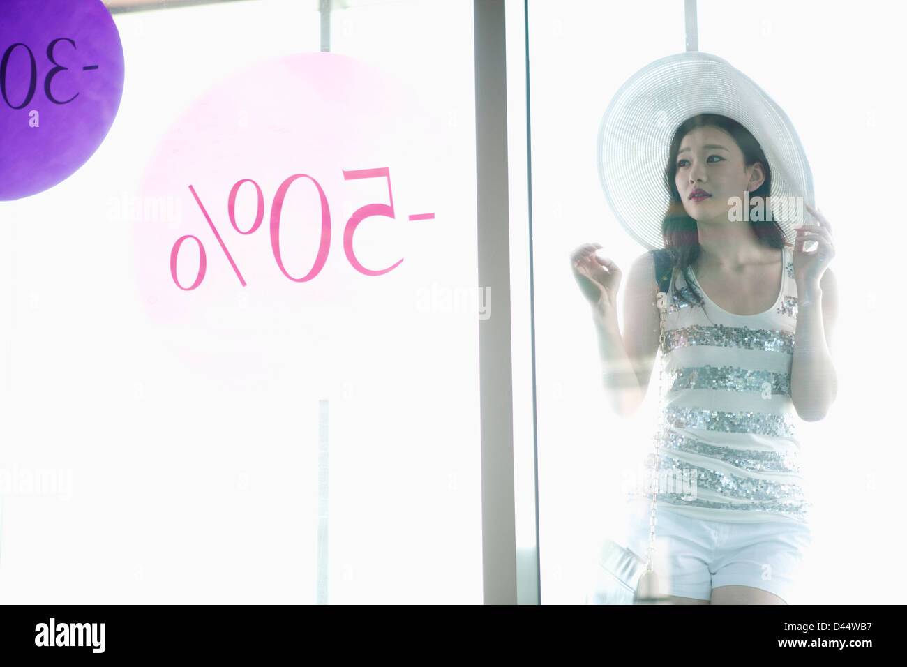 a woman looking through a shopping window with sale sign Stock Photo ...