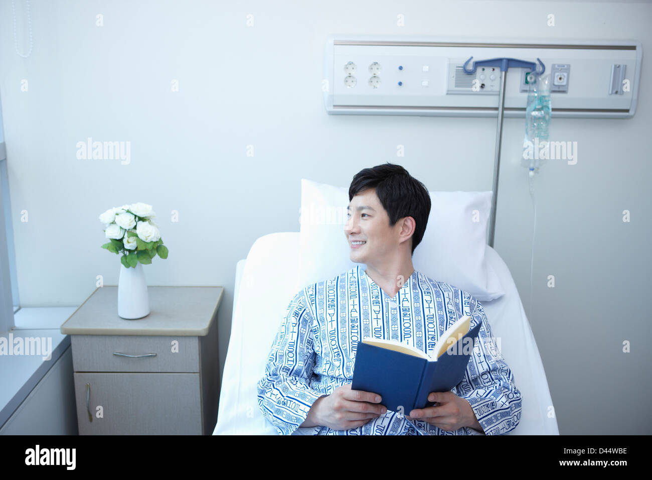 a patient lying on the bed reading a book in hospital room Stock Photo ...