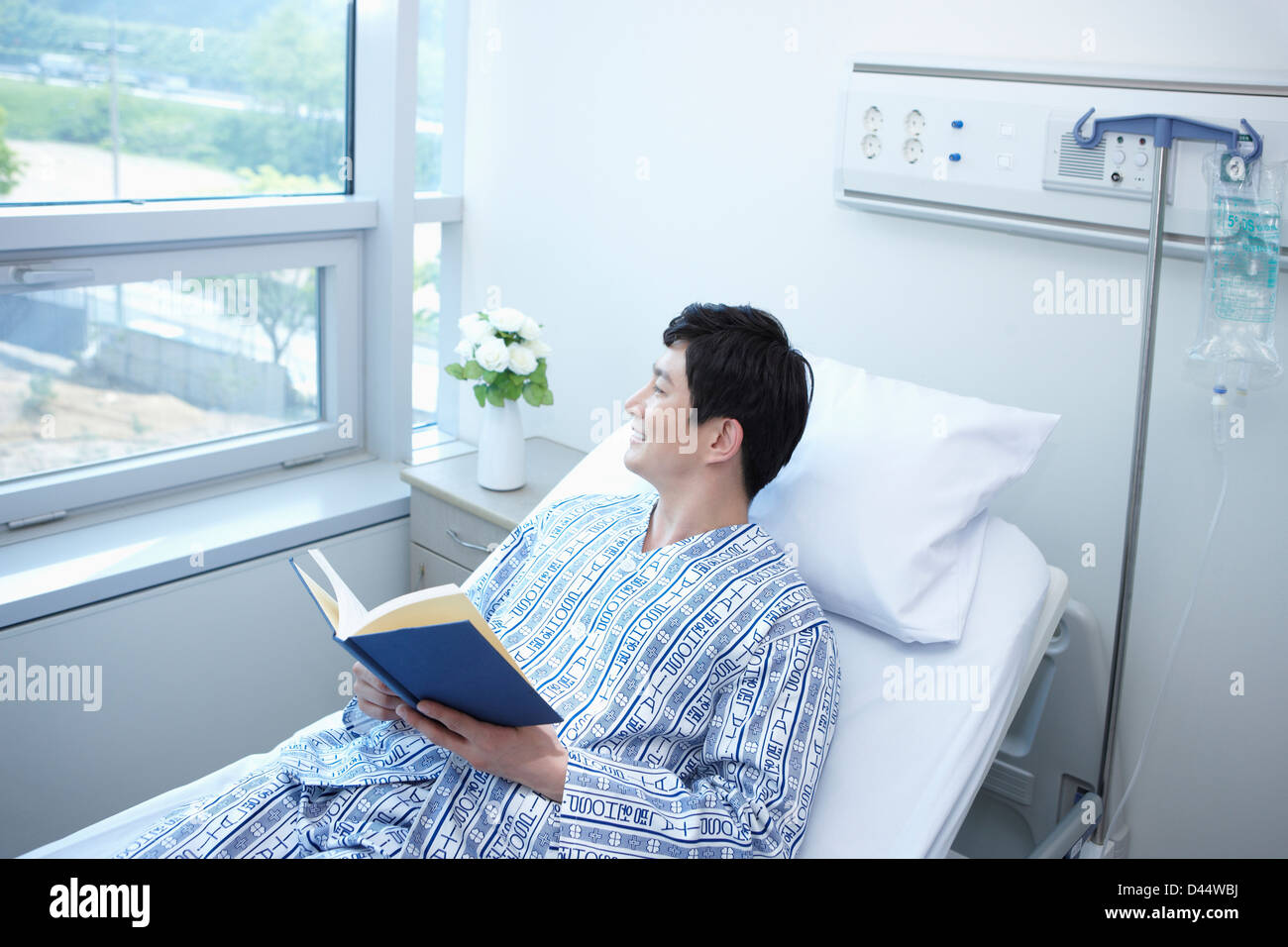 a patient lying on the bed reading a book in hospital room Stock Photo ...