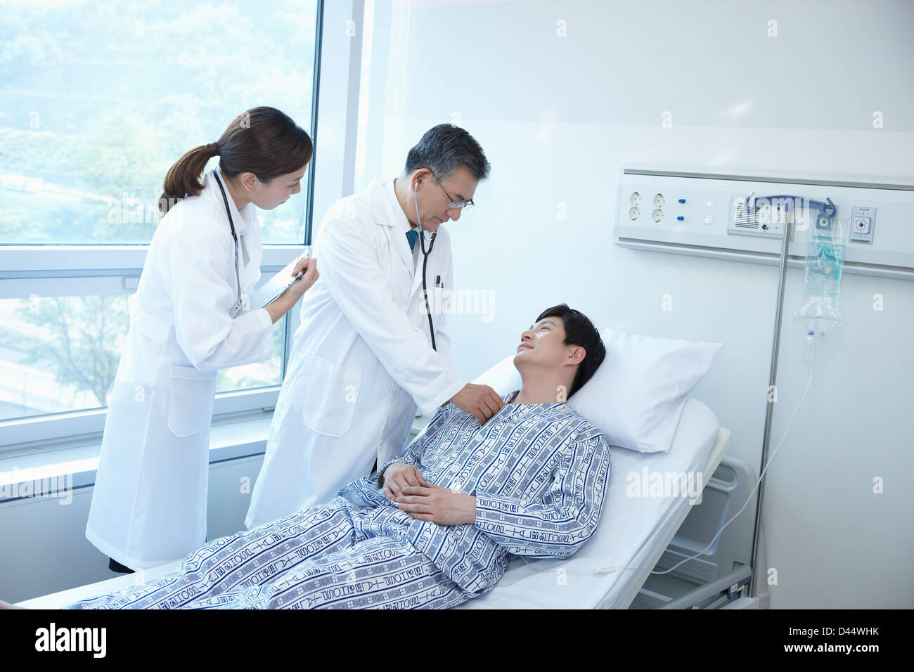 doctors examining a patient lying on the bed with a stethoscope Stock ...