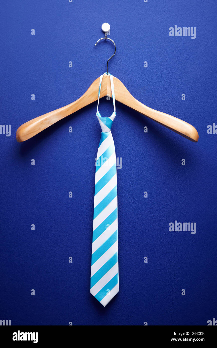 a neck tie hanging on a hanger in blue background Stock Photo - Alamy
