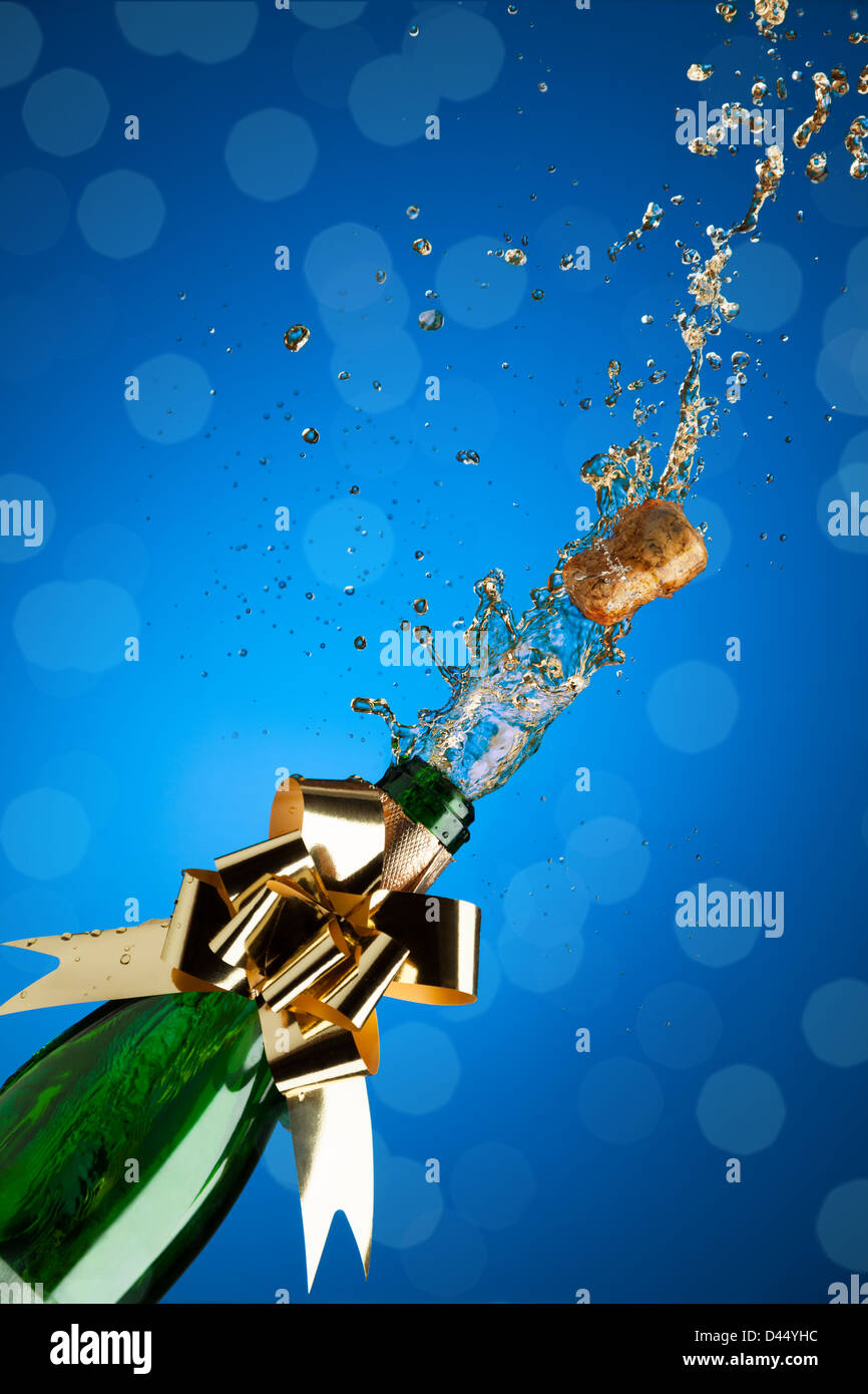 Champagne splashes from bottle and popping cork on blue background ... Champagne splashes from bottle and popping cork on blue background ...