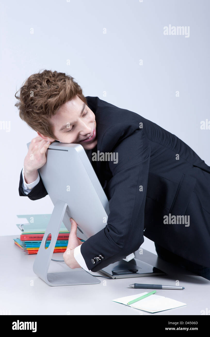 a man hugging a monitor on a desk Stock Photo - Alamy