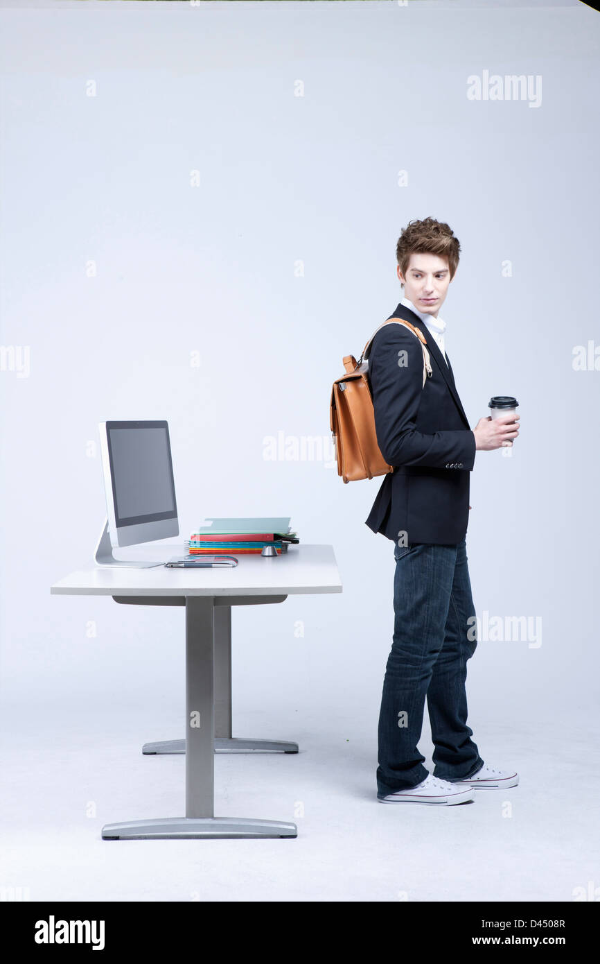 a man wearing a backpack leaving a desk Stock Photo - Alamy