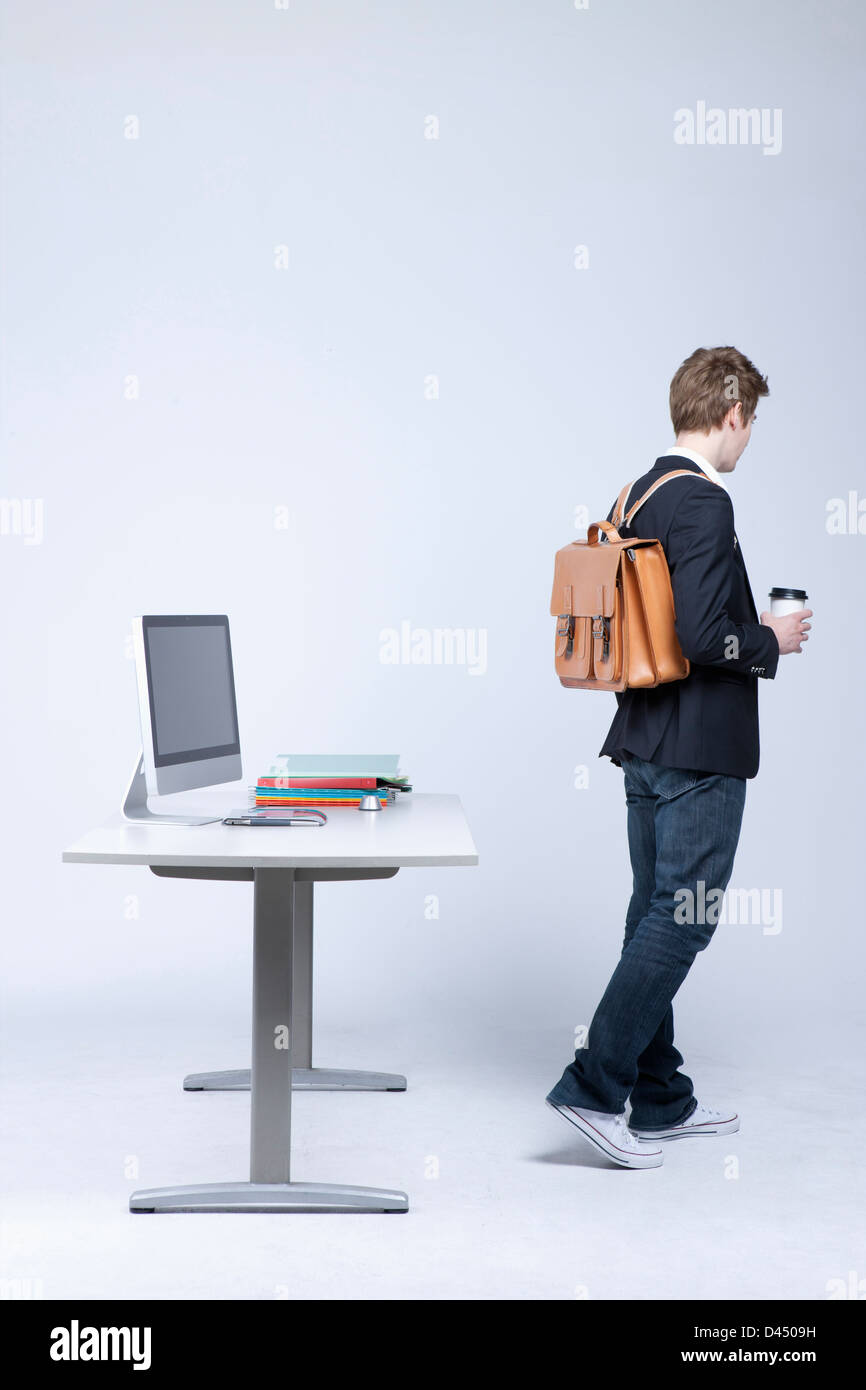 a man wearing a backpack leaving a desk Stock Photo - Alamy