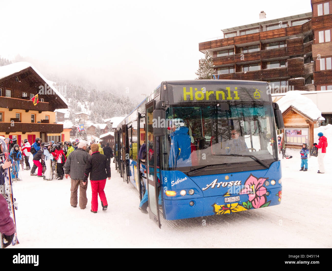 Skiers getting the ski bus in the snow for skiing on a street in Arosa ...