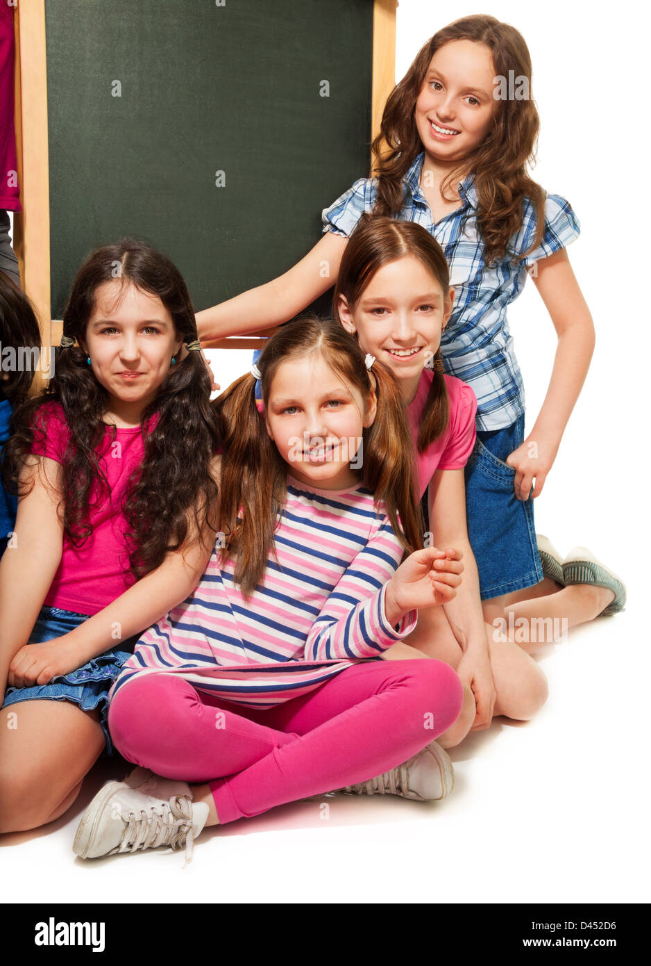 Four 10-11 girls sitting under school little blackboard, isolated on ...