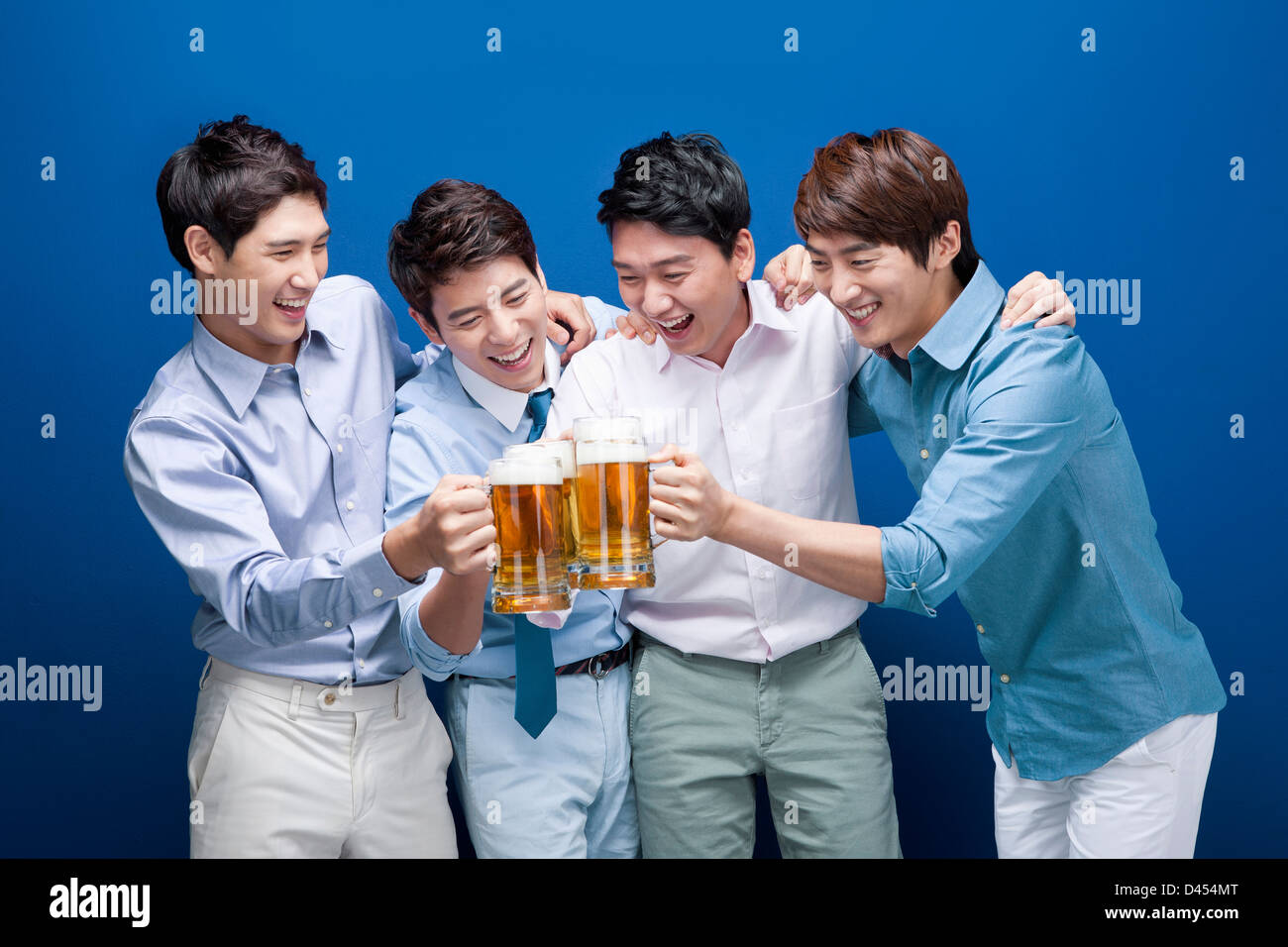 four businessmen looking at camera while toasting with beer Stock Photo ...
