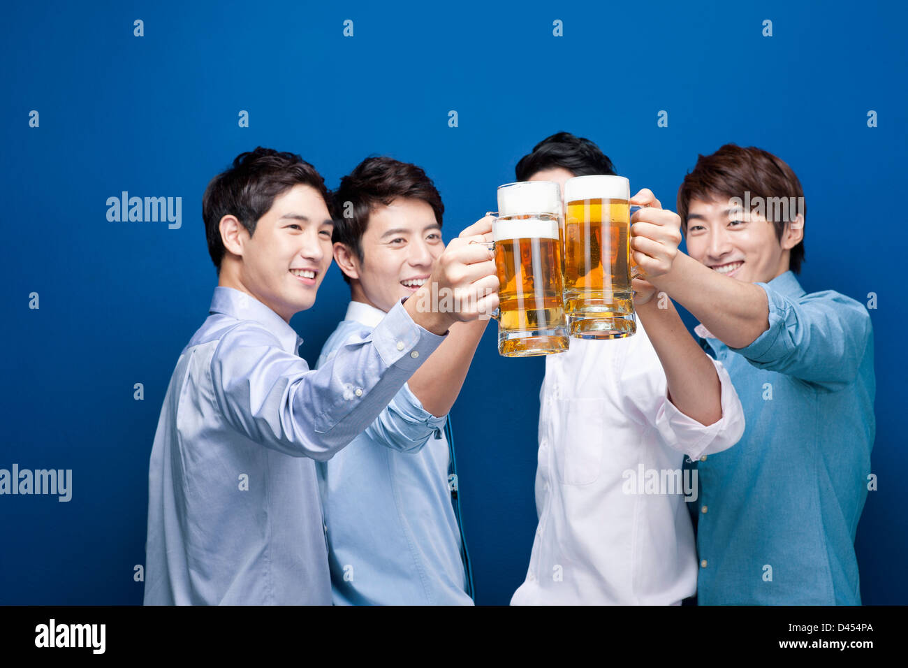 four businessmen looking at camera while toasting with beer Stock Photo ...