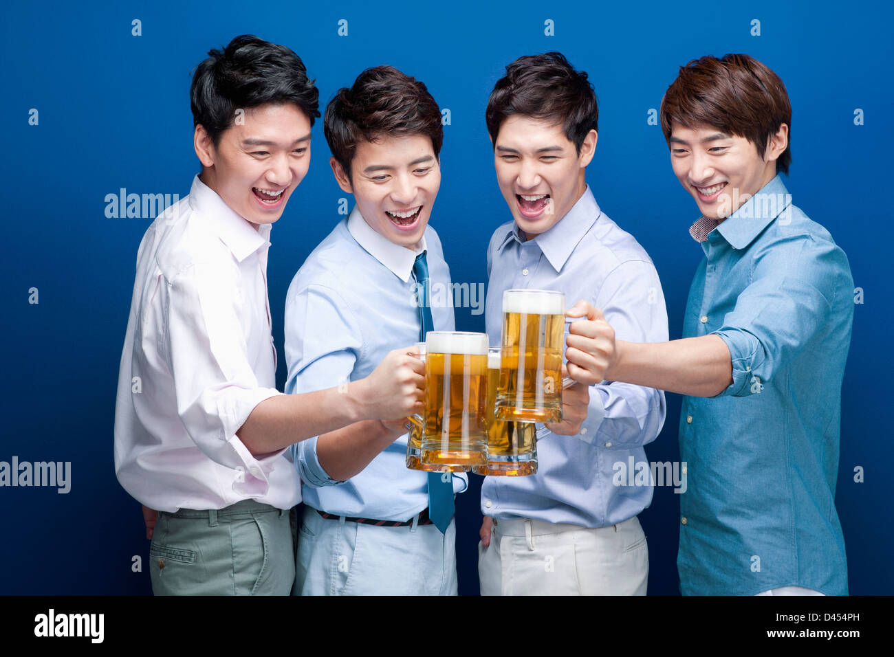 four businessmen looking at camera while toasting with beer Stock Photo ...