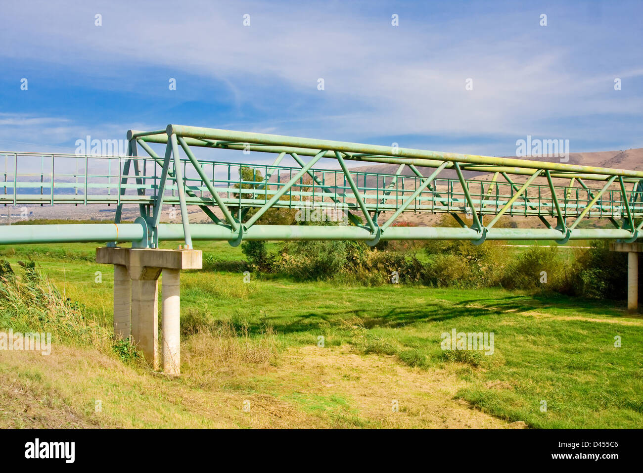 Metal pedestrian bridge across a green valley in Agamon Hula national ...
