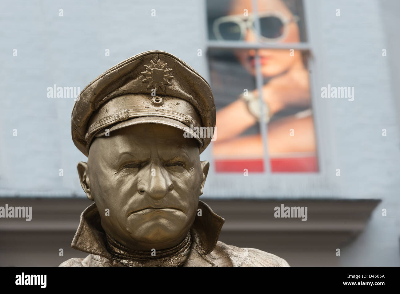 Gold painted male mime artist by a street advertisement Covent Garden ...