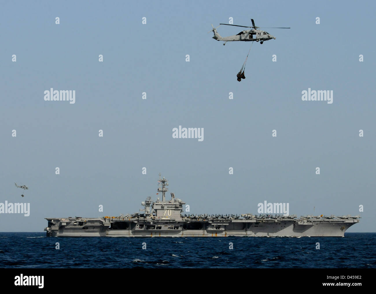A helicopter transfers supplies to a naval vessel in the Arabian Sea as ...