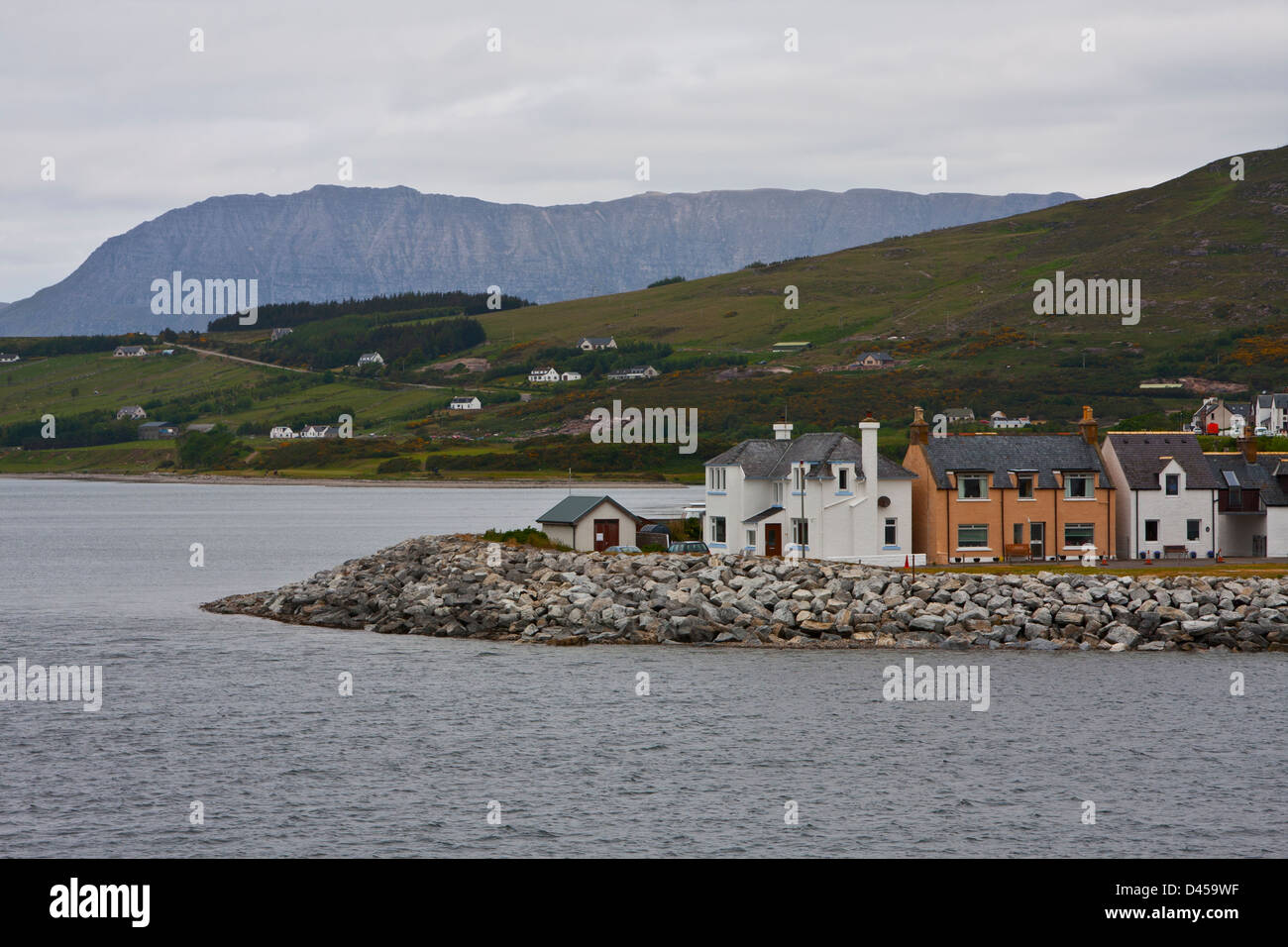 A long sand spit that forms the arm of the harbour at Ullapool is lined ...