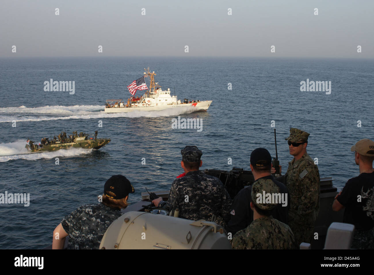 A riverine command boat operates alongside the U.S. Coast Guard Cutter ...