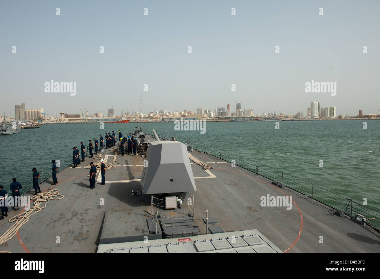 Sailors aboard the USS Nitze stand on the rails as the ship departs ...