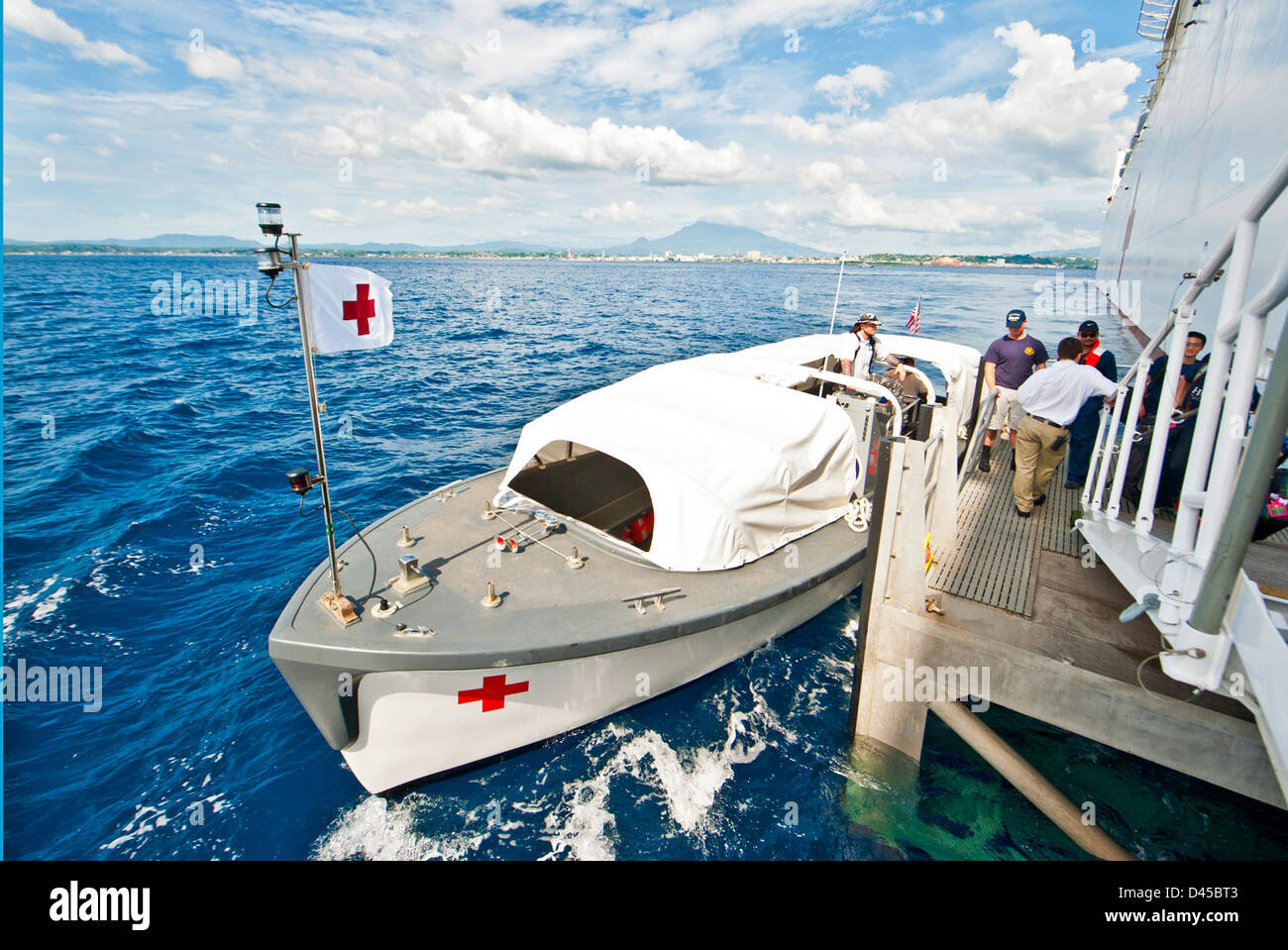 Military and civilian personnel board a support boat attached to the ...