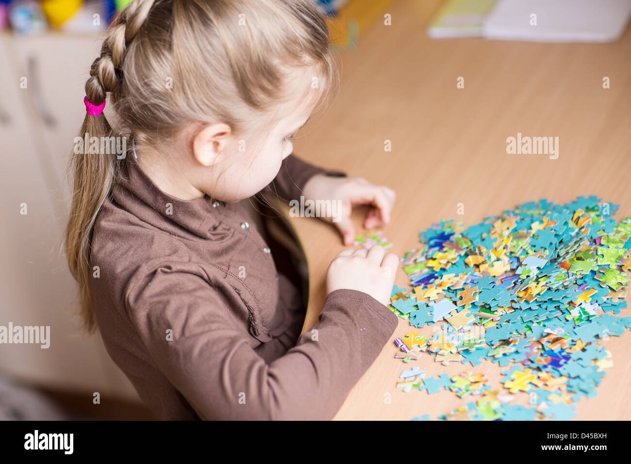Cute little girl playing puzzles at the table Stock Photo - Alamy