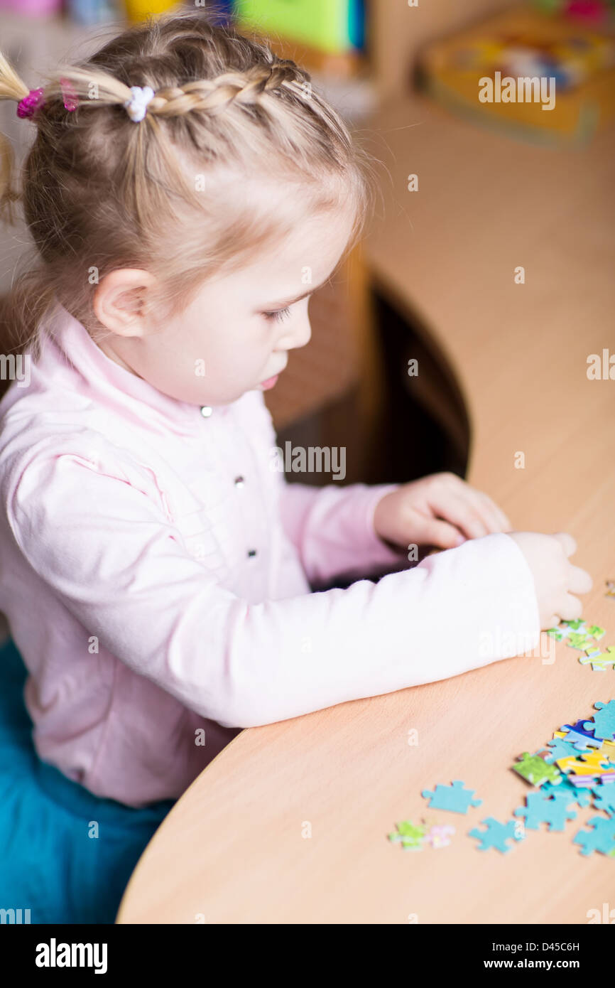 Cute little girl playing puzzles at the table Stock Photo - Alamy