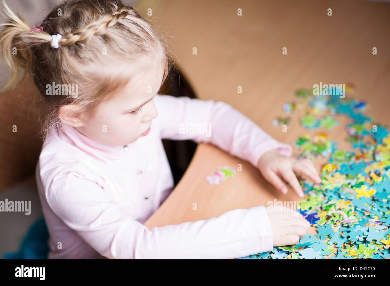 Cute little girl playing puzzles at the table Stock Photo - Alamy