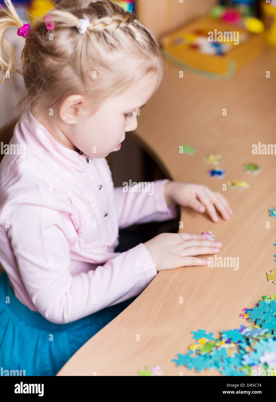 Cute little girl playing puzzles at the table Stock Photo - Alamy